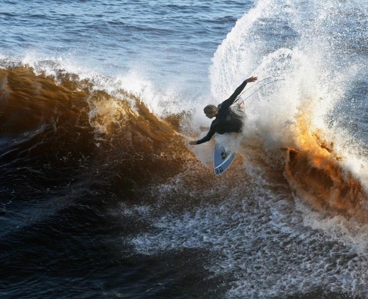 Foto de surfista dominando uma grande onda com um jato de água